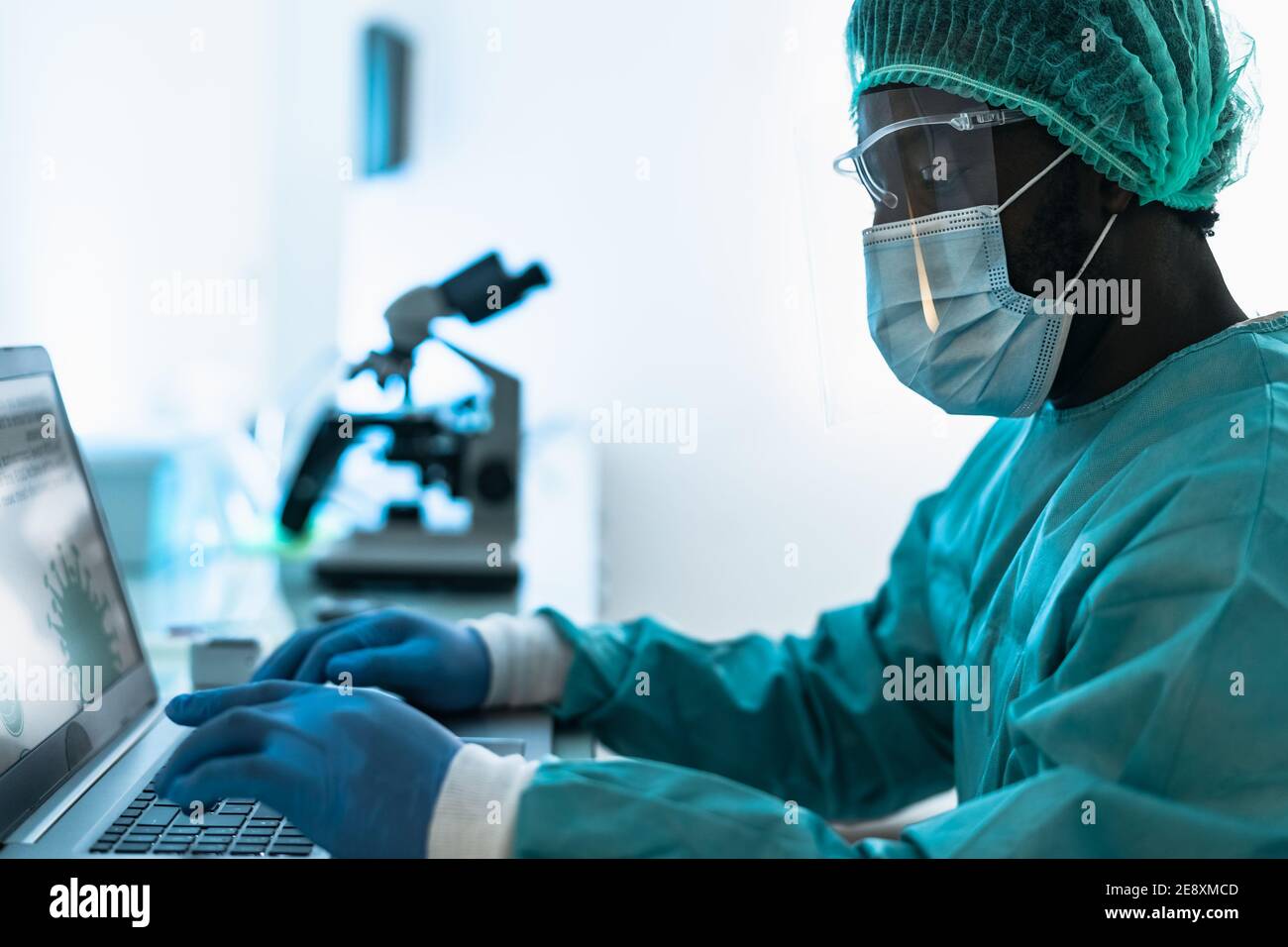 Medical worker wearing personal protective equipment using computer ...