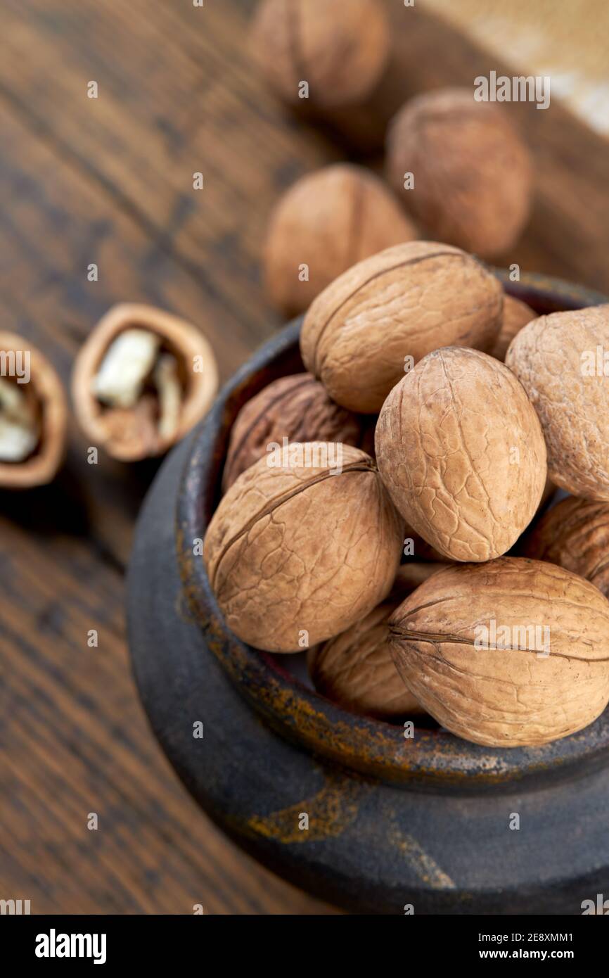group of fresh raw walnuts in clay pot on grunge wooden background ...