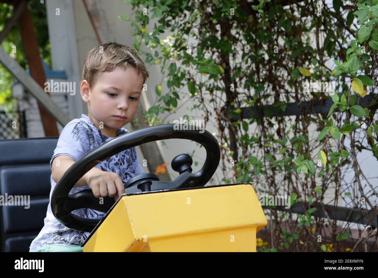 Serious kid driving a tractor at the farm Stock Photo - Alamy