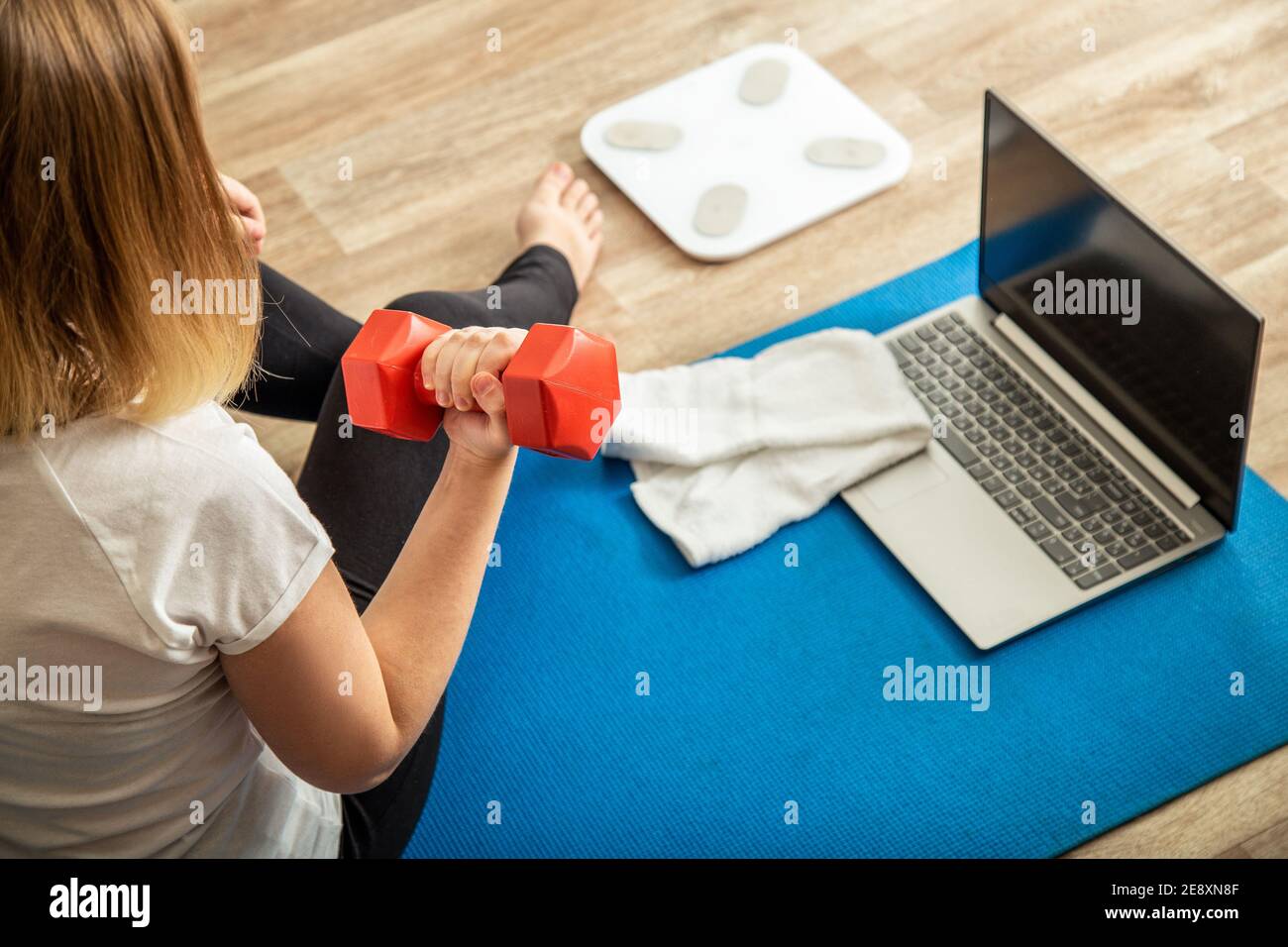 Sporty woman using dumbbells making fitness at home via laptop by ...
