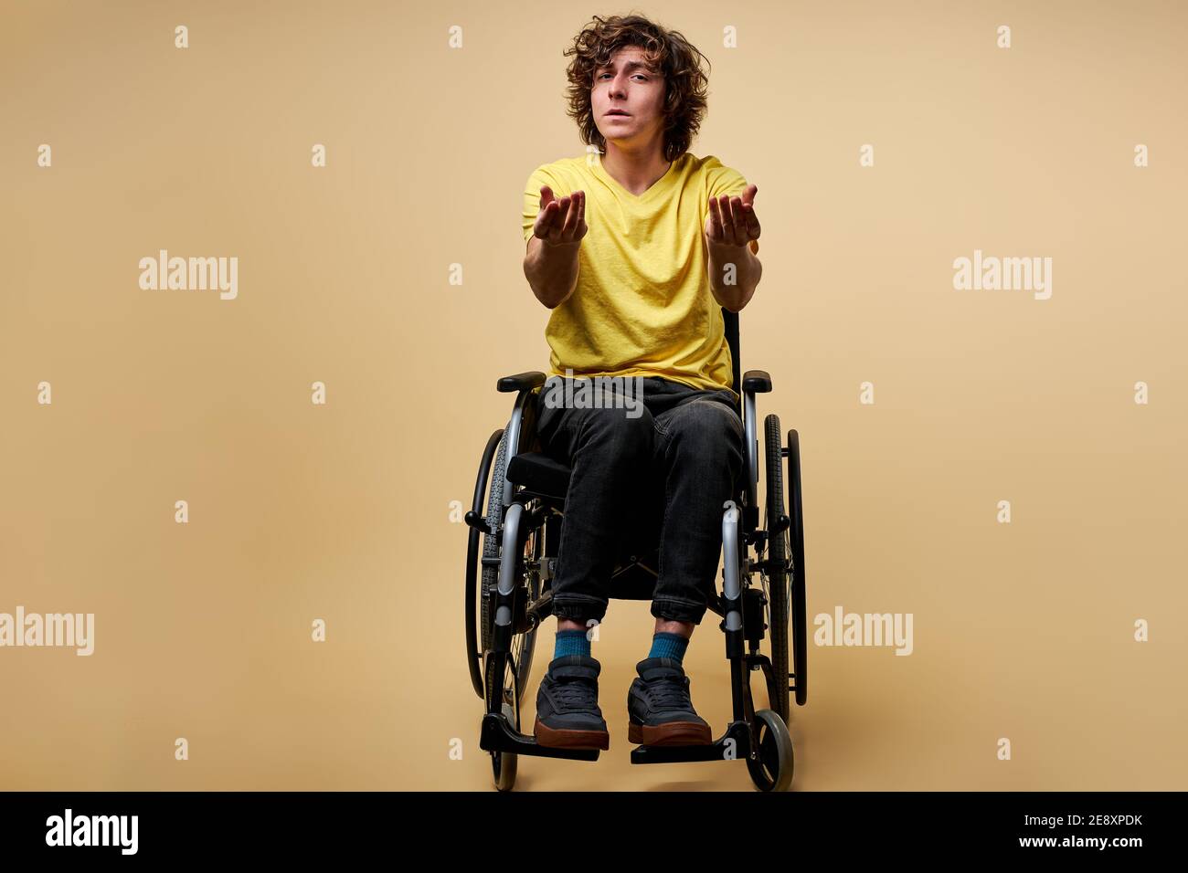 disabled man isolated on beige studio background, asking for help ...