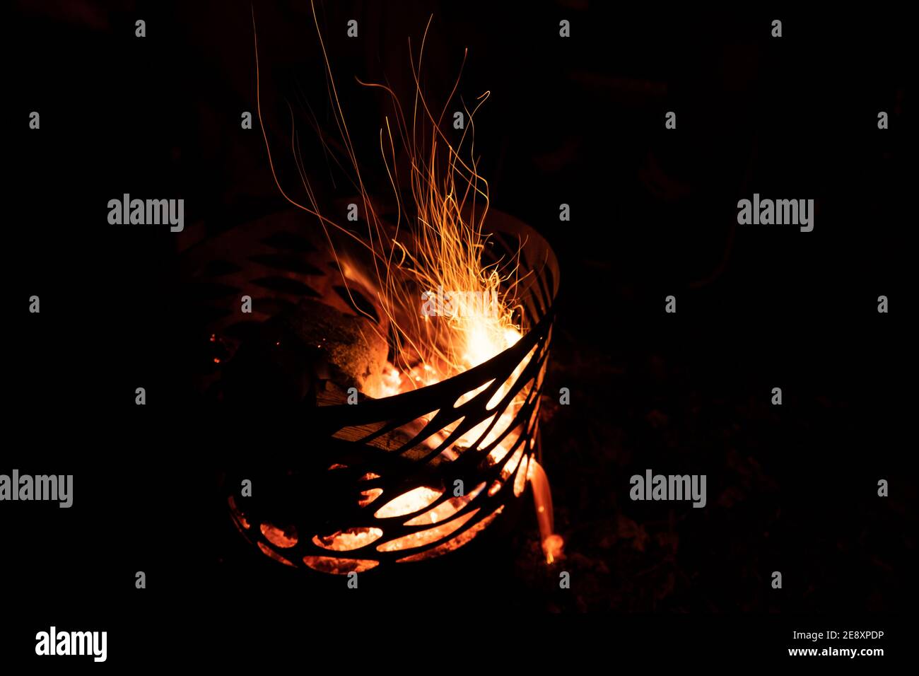Long exposure photograph of a camp pit fire with a piece of wood on it ...