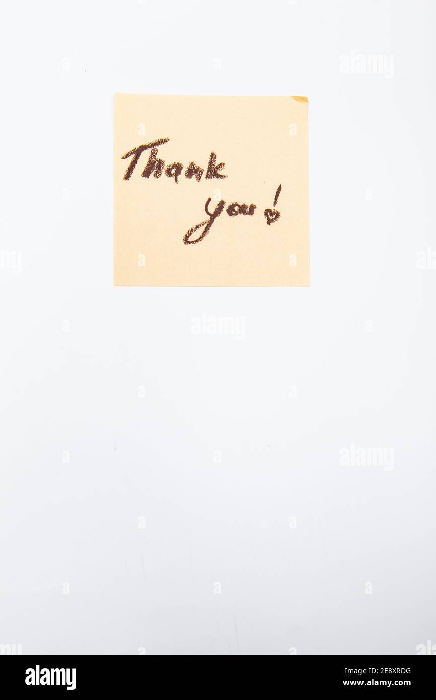 Vertical shot of a thank you note handwrtitten on yellow sticky paper ...