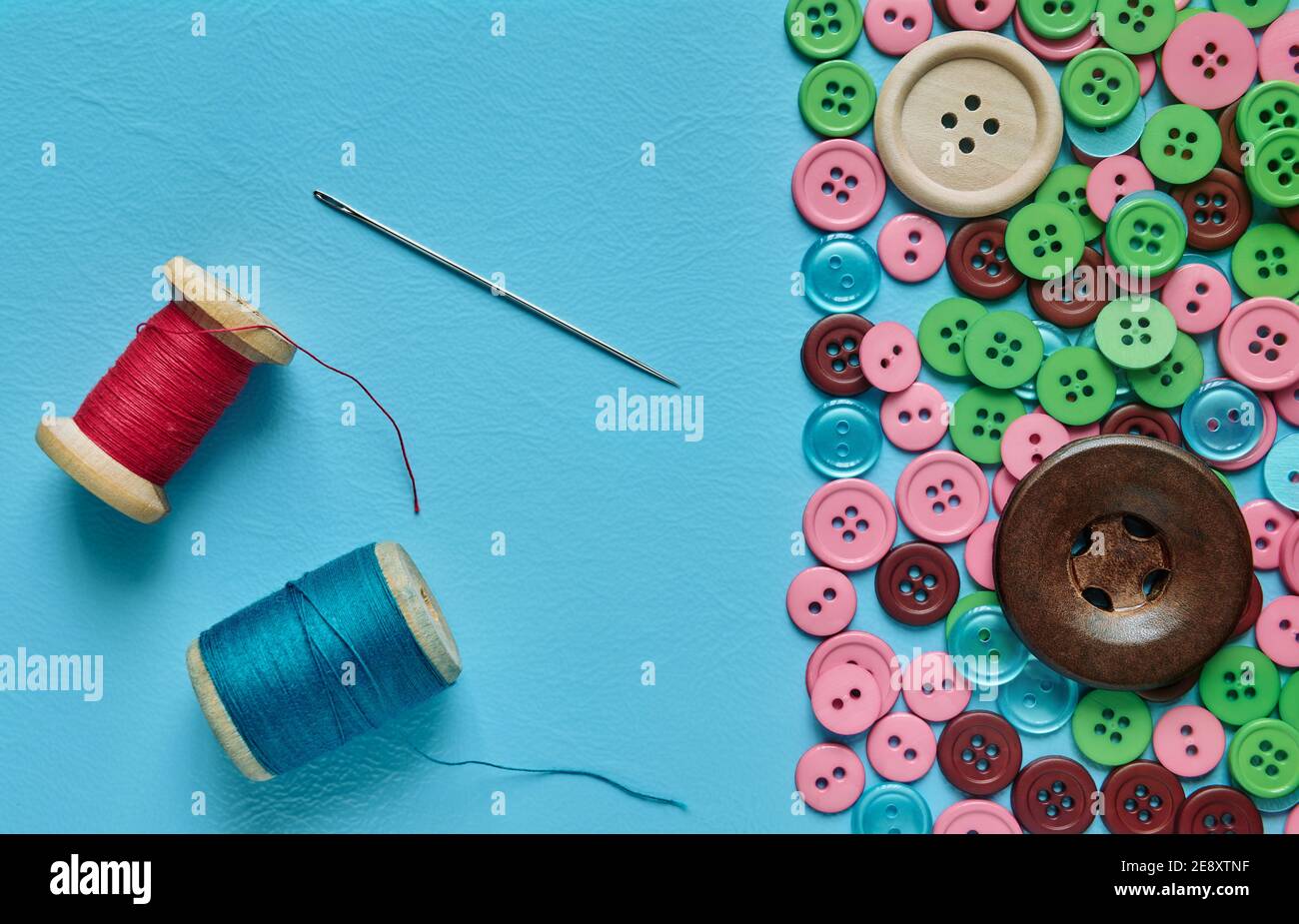 Sewing buttons and thread reels on a blue background. Flat laye Stock ...