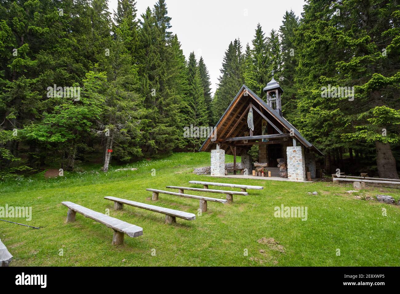 Wooden outdoor church in the middle of a grass-covered field surrounded ...