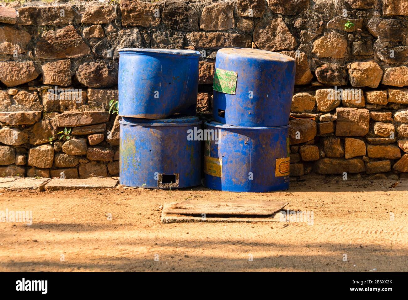 4 blue buckets standing in front of a dusty brick wall of sand stone ...
