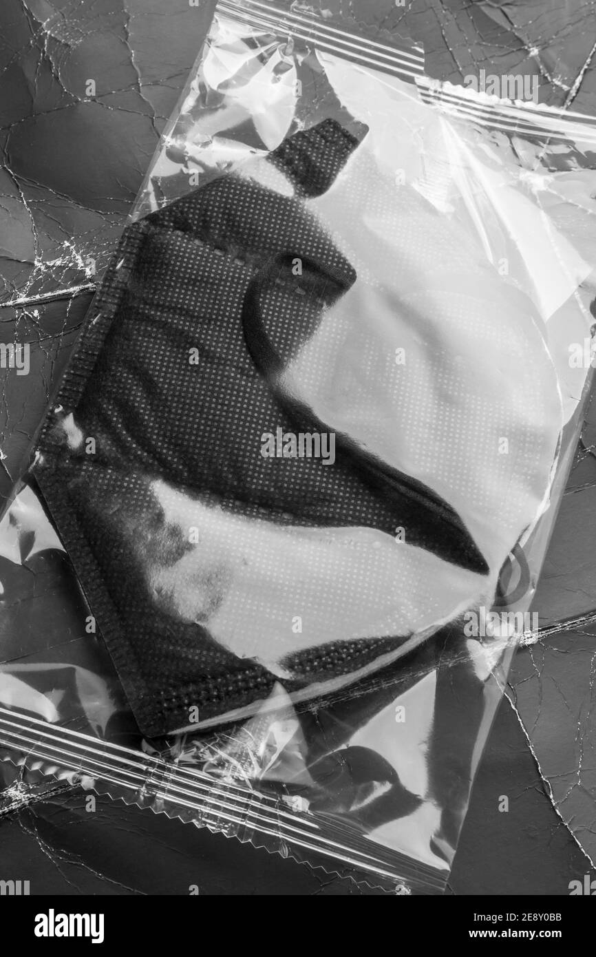 New black medical respiratory mask in transparent pack on crumpled ...