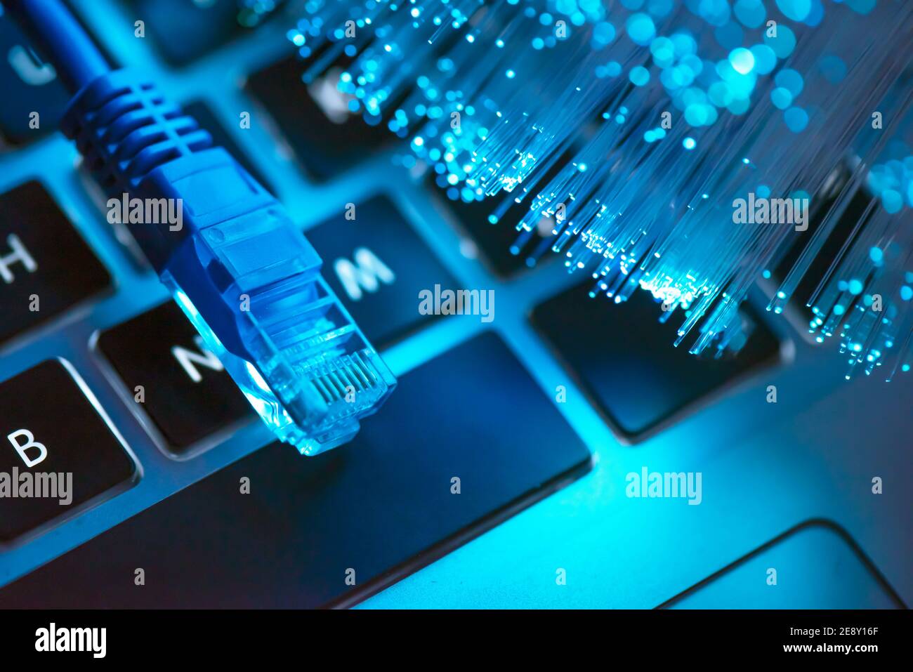 Internet cable, RJ-45 plug on laptop keyboard. High speed fiber optic ...