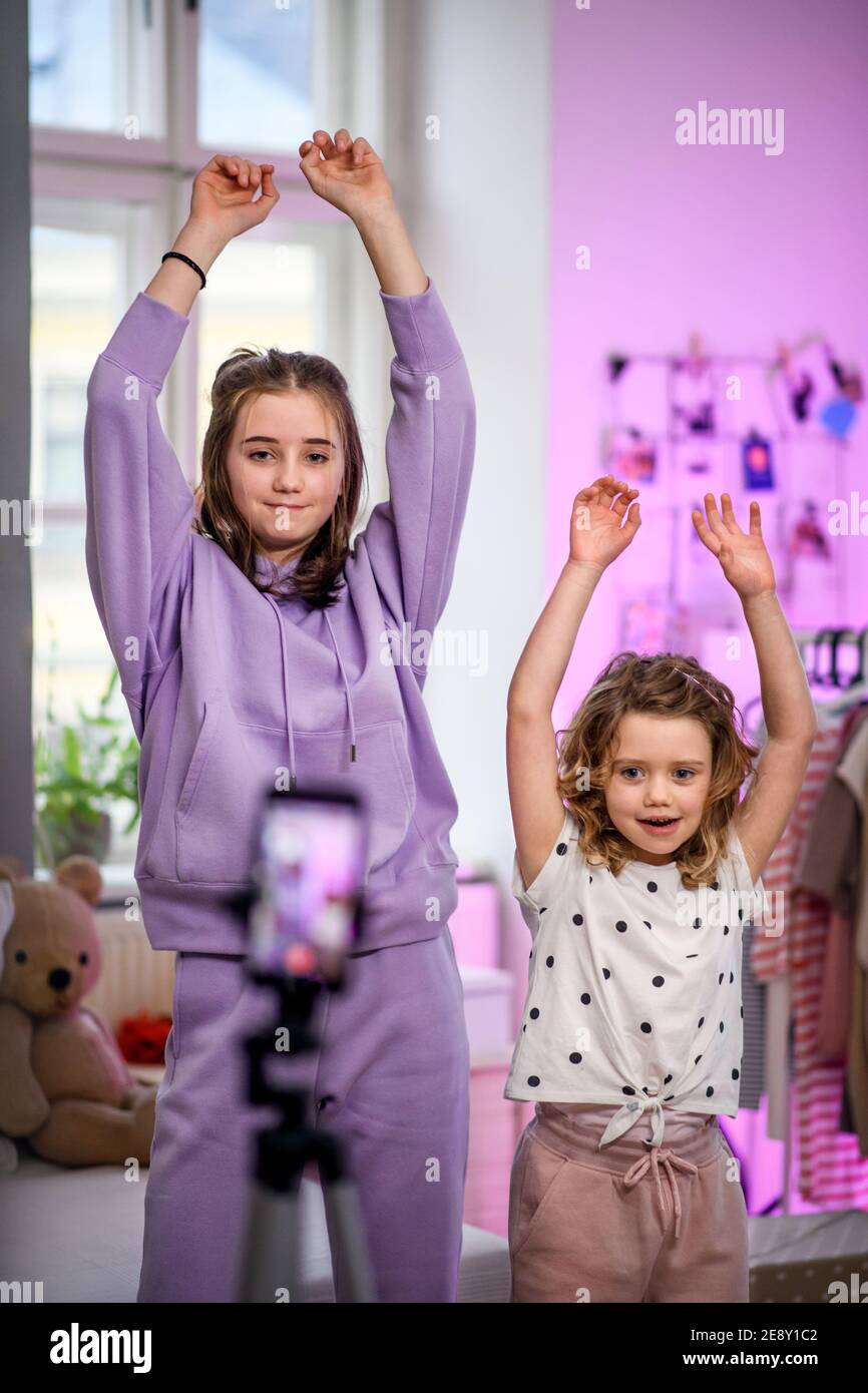 Sisters indoors at home, making video with smartphone. Lockdown concept ...
