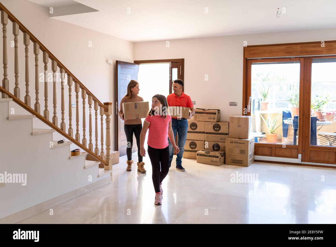 Family carrying boxes moving into a new house Stock Photo - Alamy
