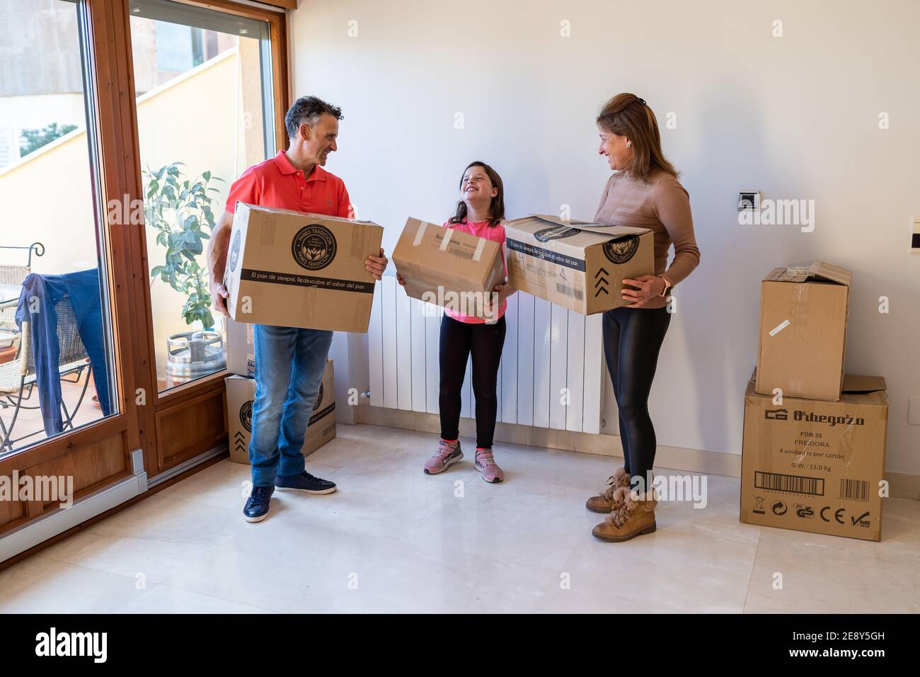 Family carrying boxes moving into a new house Stock Photo - Alamy