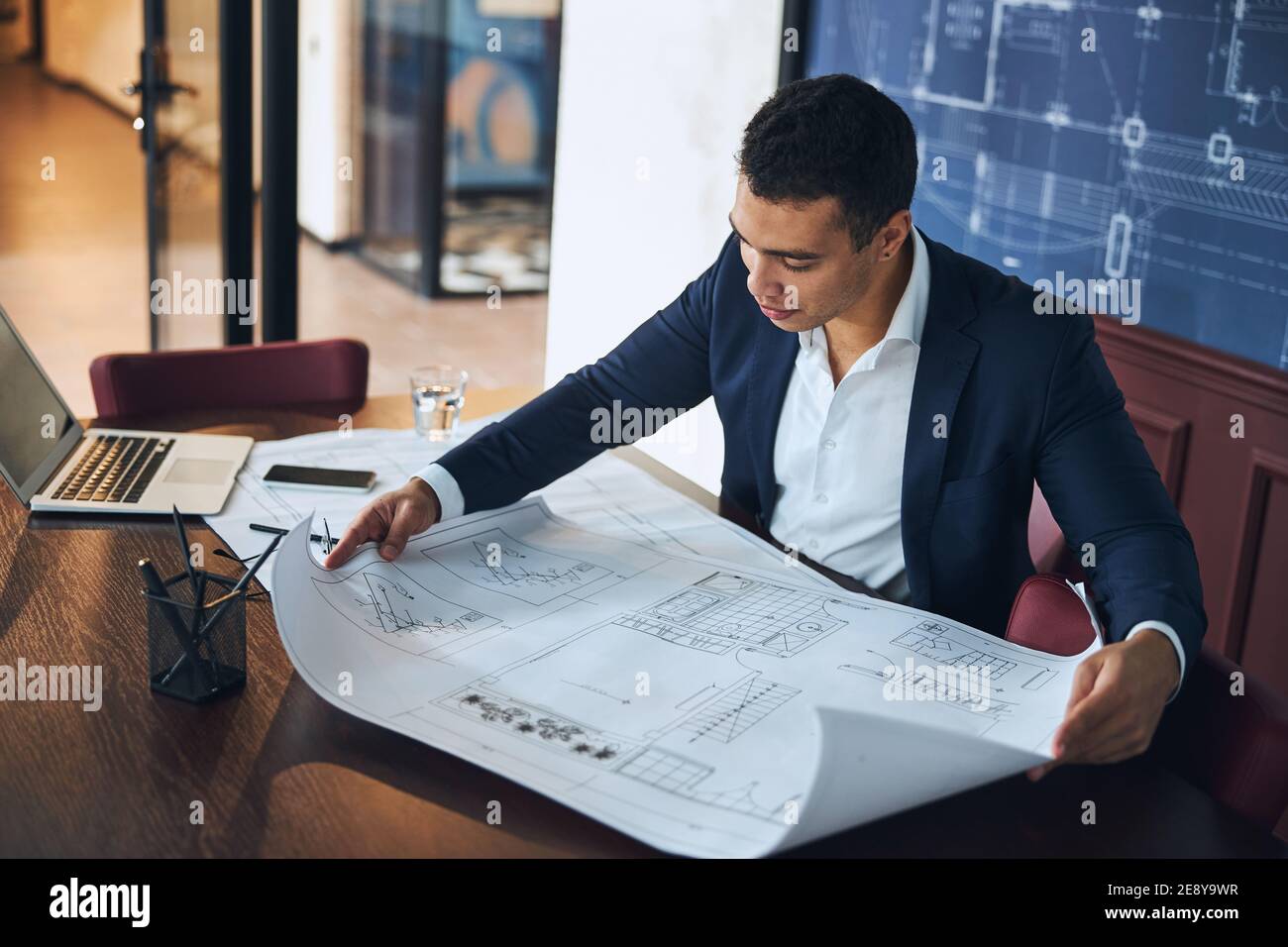 Dark-haired professional engineer scrutinizing a technical drawing ...