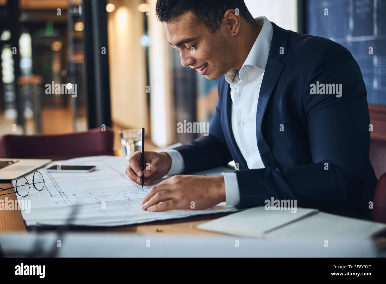 Smiling cute engineer creating a new building plan Stock Photo - Alamy