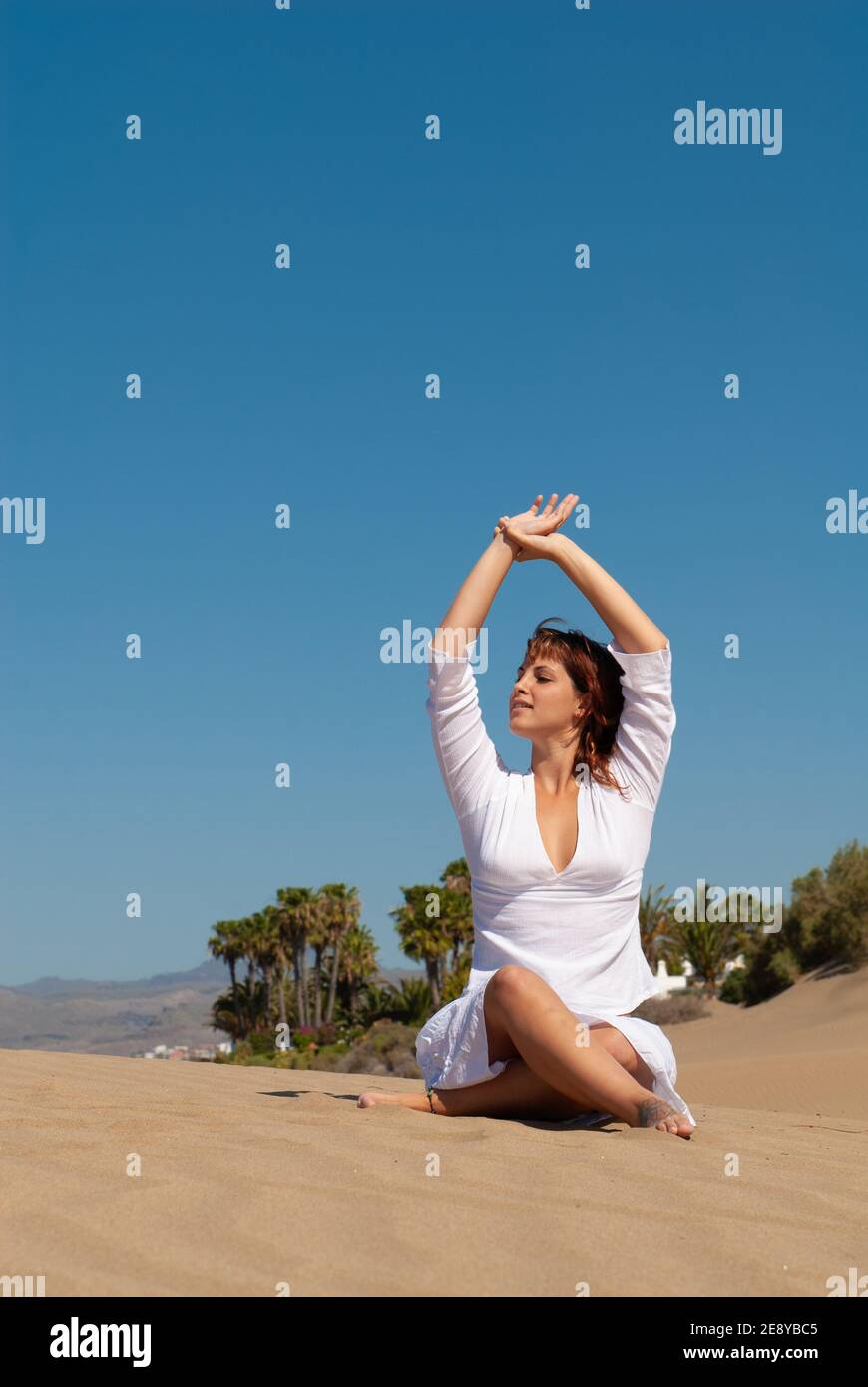 woman on sand dunes in spring or summer doing yoga poses and meditation ...