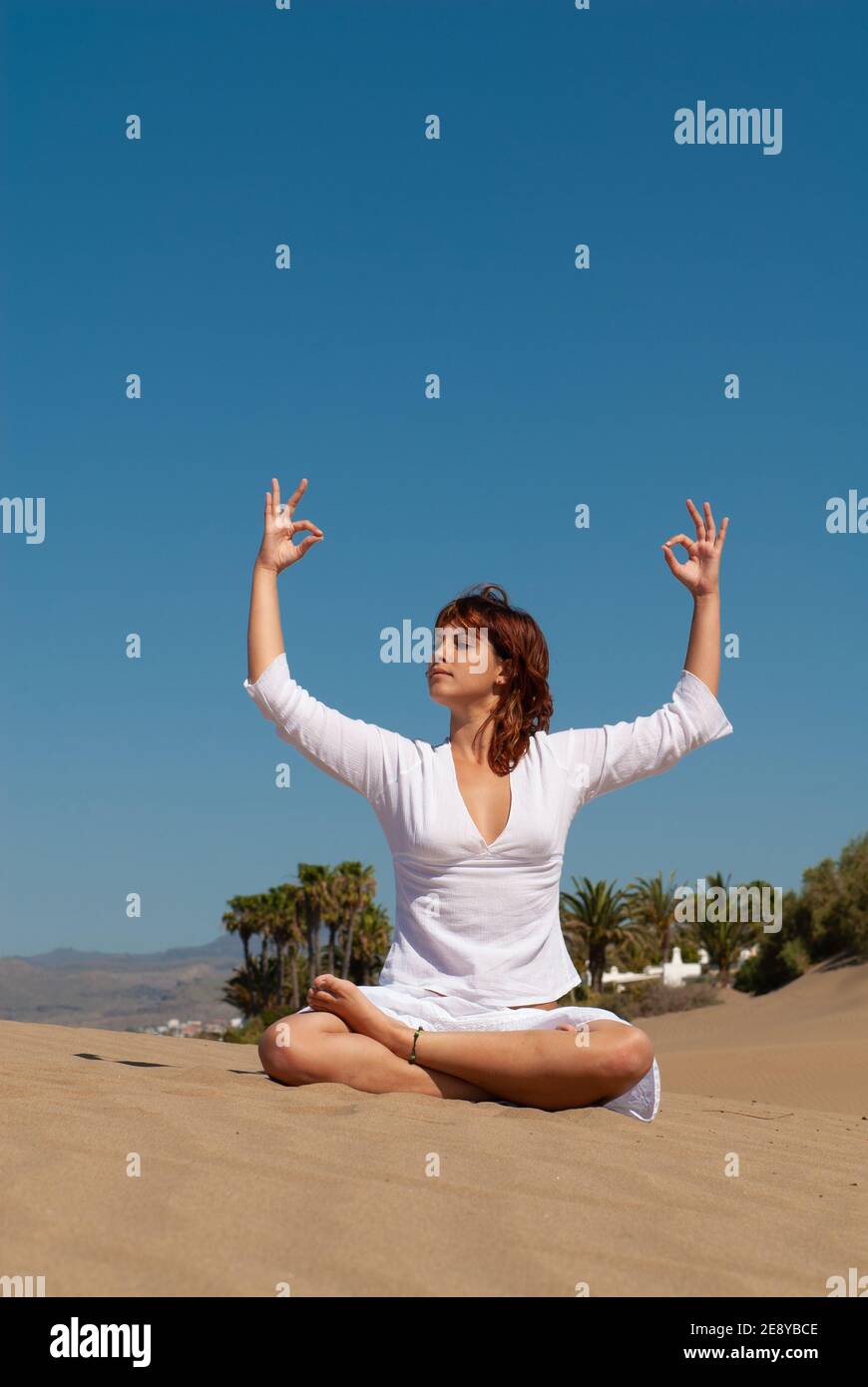 woman on sand dunes in spring or summer doing yoga poses and meditation ...
