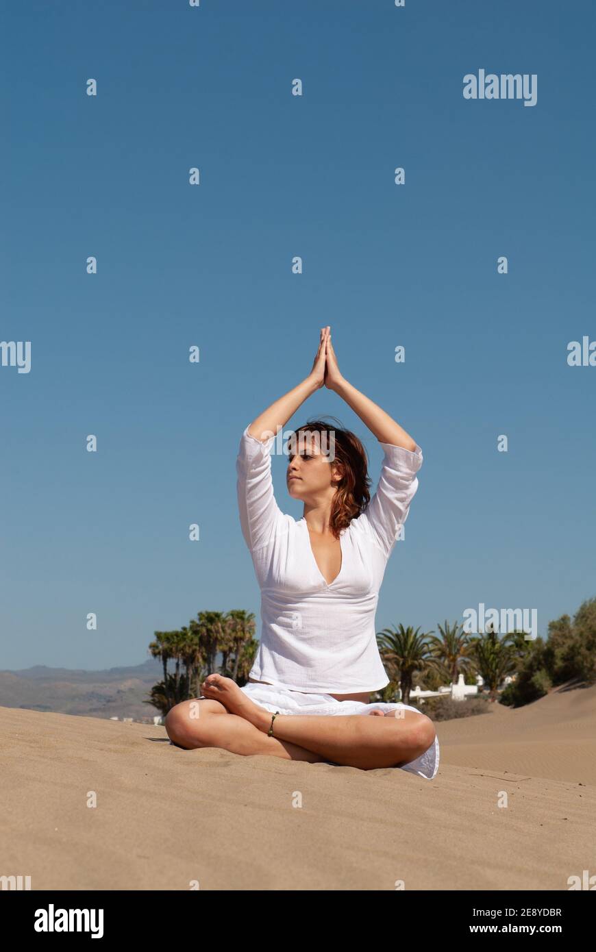 woman on sand dunes in spring or summer doing yoga poses and meditation ...