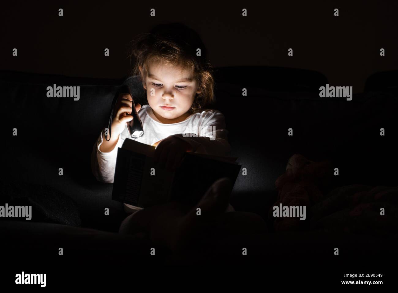 toddler caucasian girl reading book at hight with flashlight. Unplugged ...