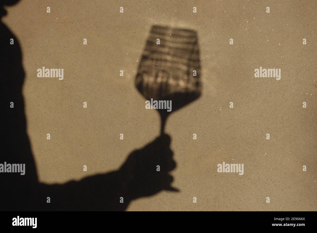 Shadow on the wall of a female sommelier alone with a glass of wine ...
