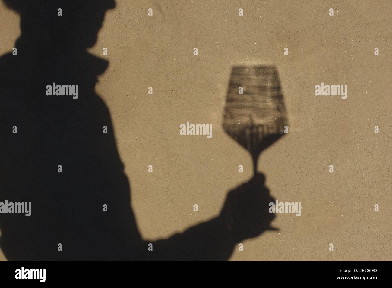 Shadow on the wall of a female sommelier alone with a glass of wine ...