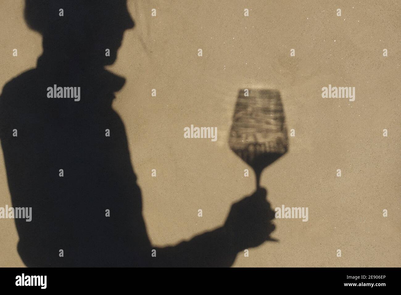 Shadow on the wall of a female sommelier alone with a glass of wine ...