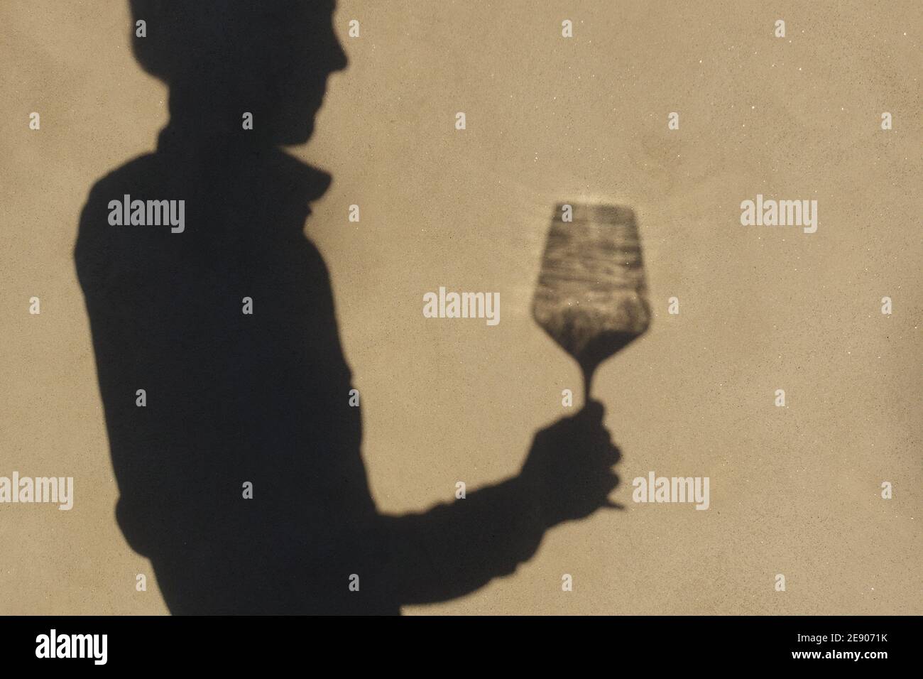 Shadow on the wall of a female sommelier alone with a glass of wine ...