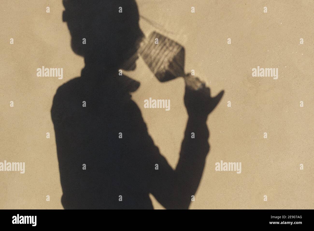 Shadow on the wall of a female sommelier alone with a glass of wine ...