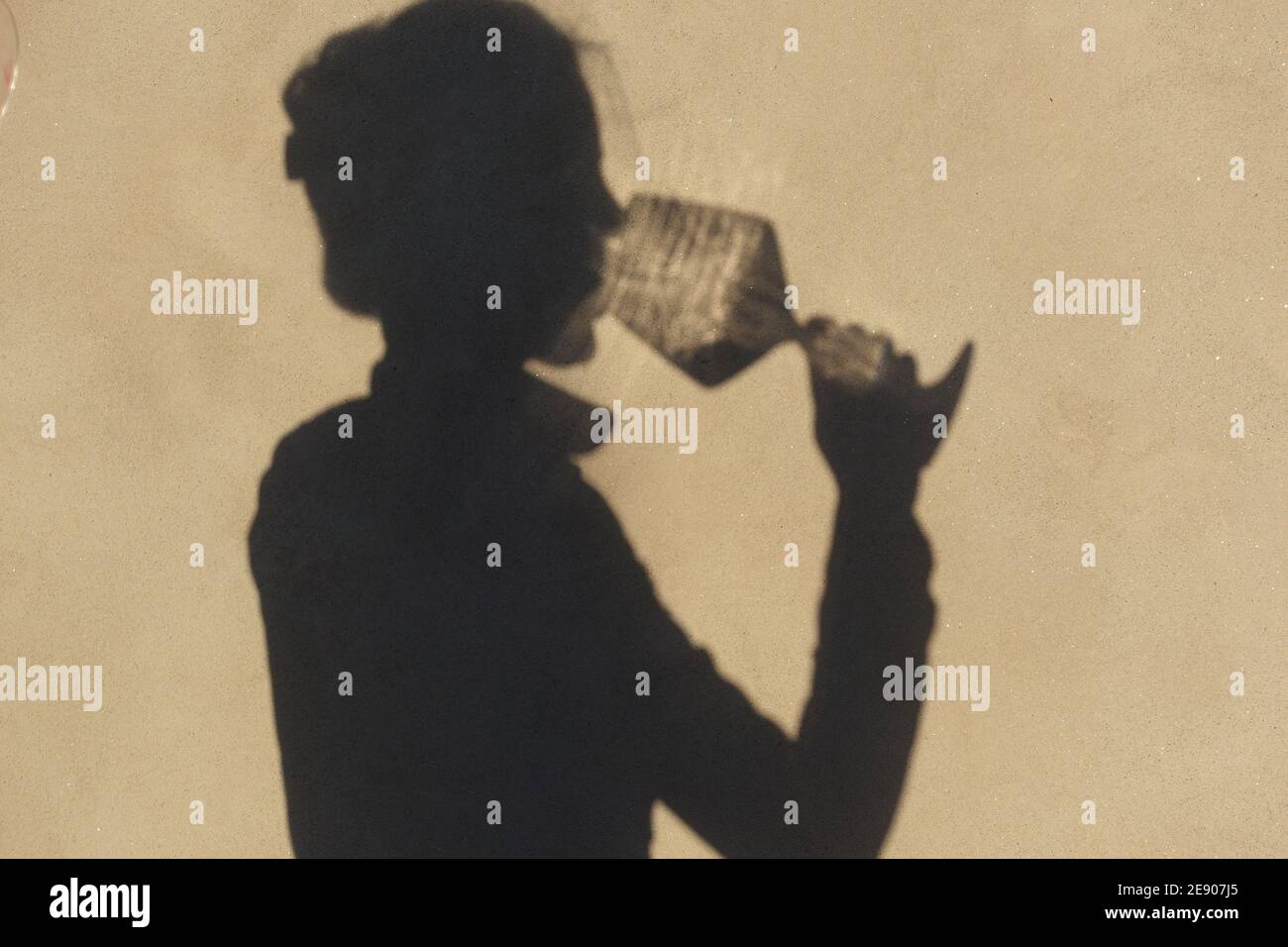 Shadow on the wall of a female sommelier alone with a glass of wine ...