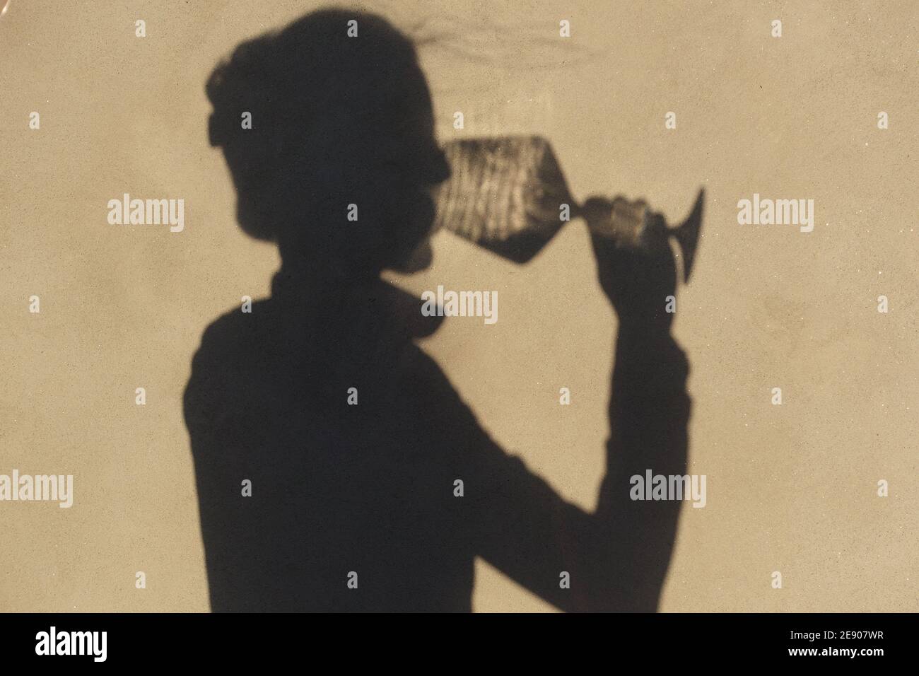 Shadow on the wall of a female sommelier alone with a glass of wine ...