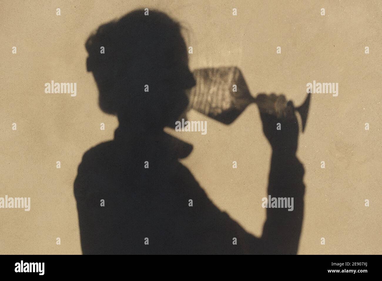 Shadow on the wall of a female sommelier alone with a glass of wine ...