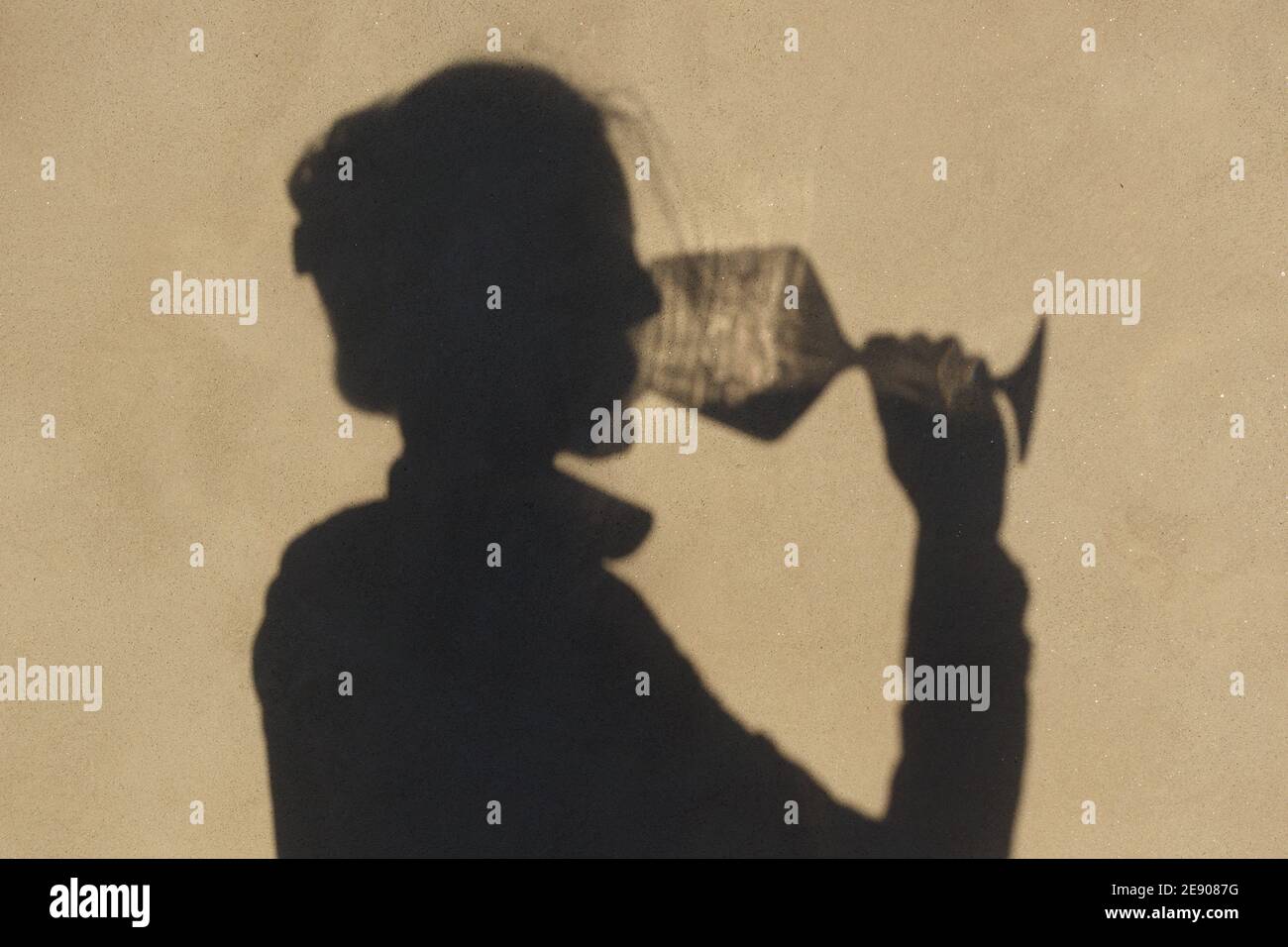 Shadow on the wall of a female sommelier alone with a glass of wine ...