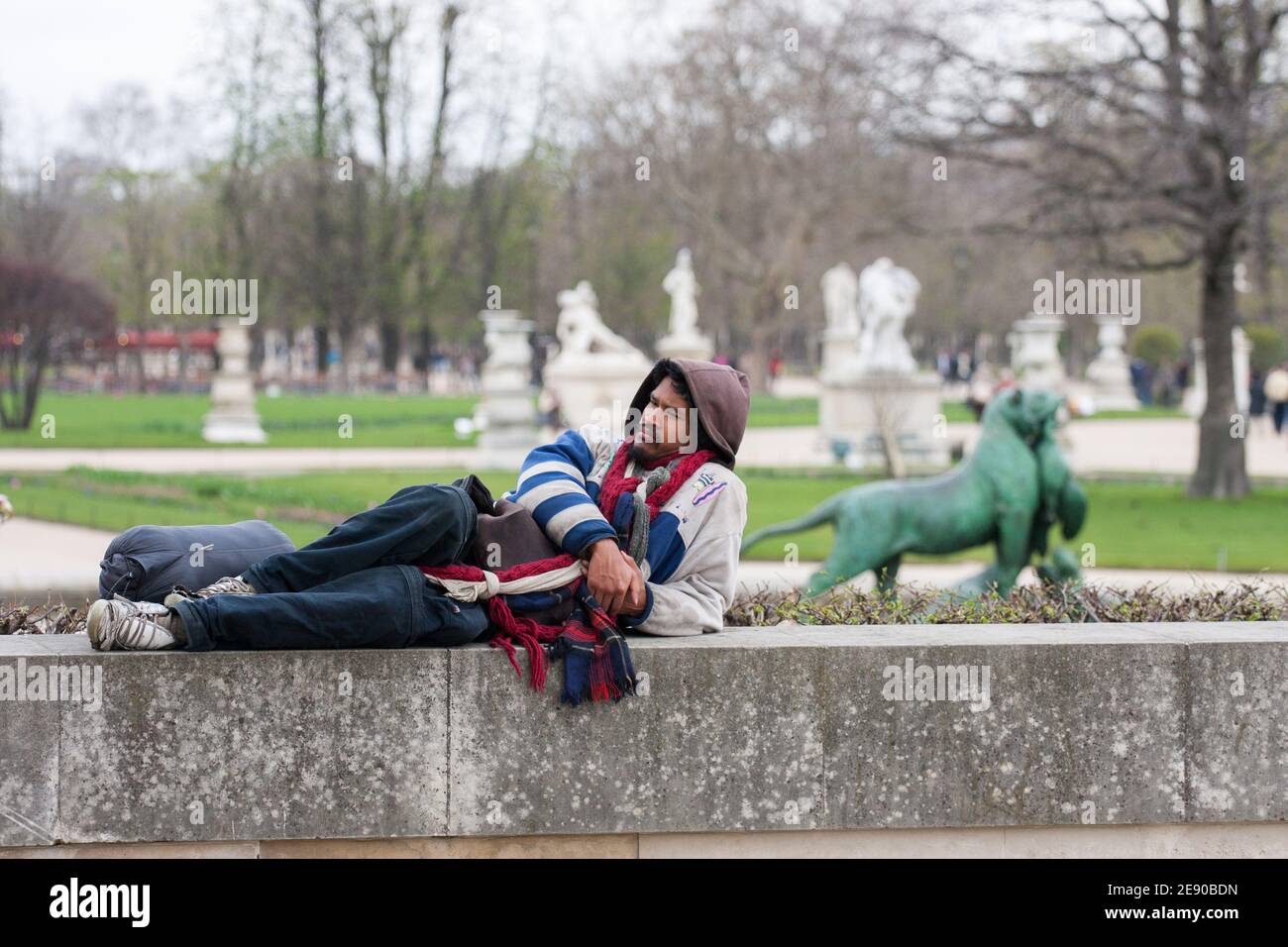 A homeless man lies on a stone curb in the park Stock Photo - Alamy