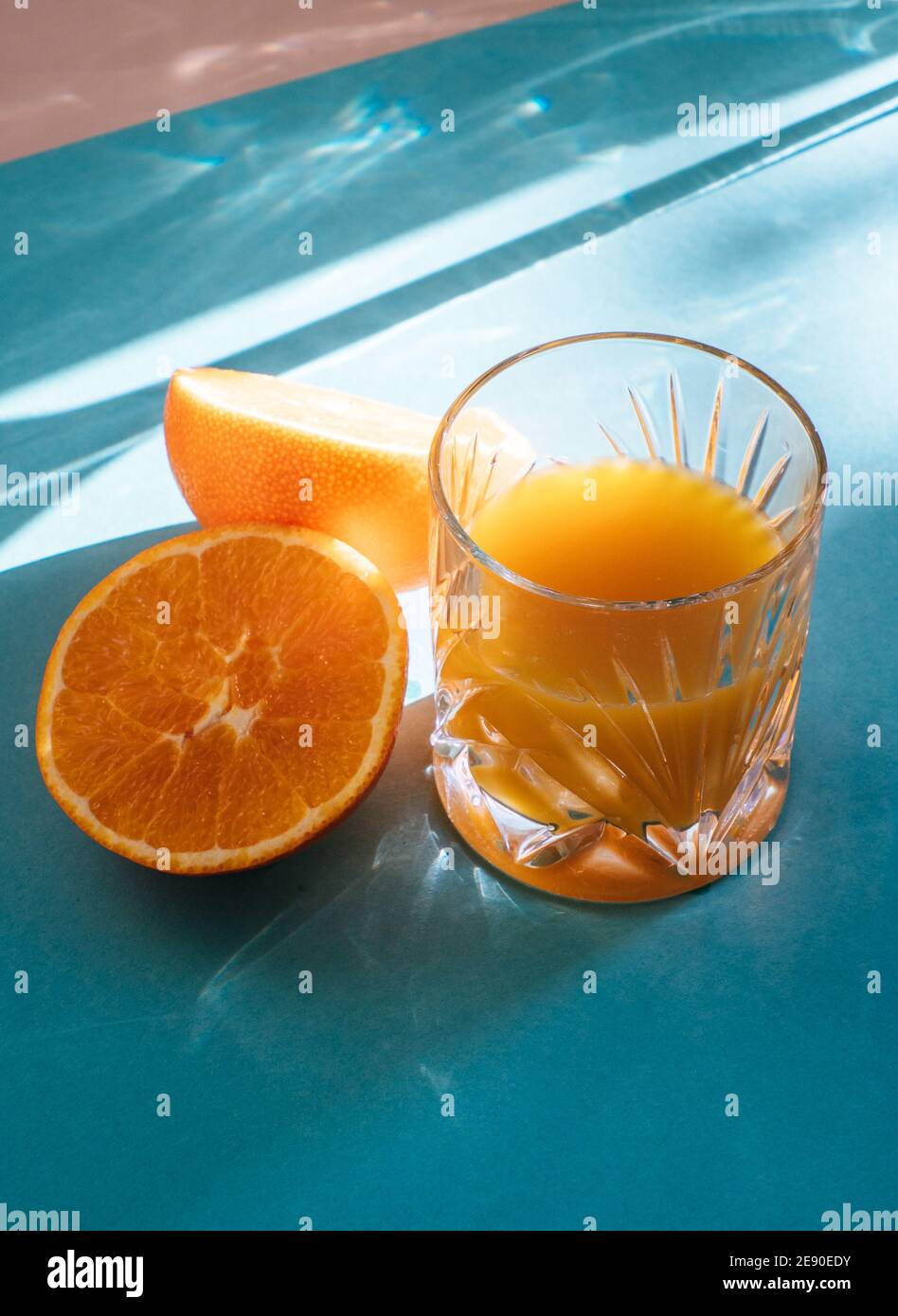 Glass of fresh squeezed orange juice isolated on turquoise blue ...