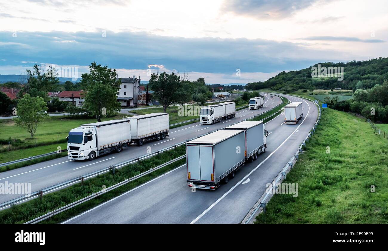 Convoys of White transportation trucks passing each other on a highway ...