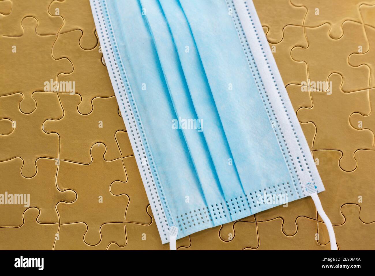 Face mask against gold puzzle pieces reflects concept of pandemic ...
