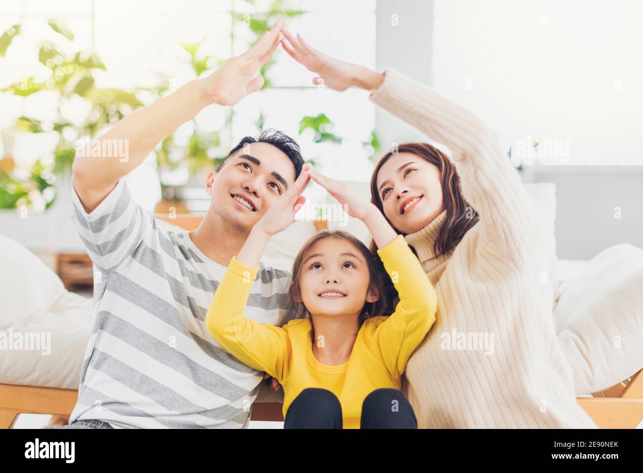 Happy asian family forming house roof with their hands at home Stock ...
