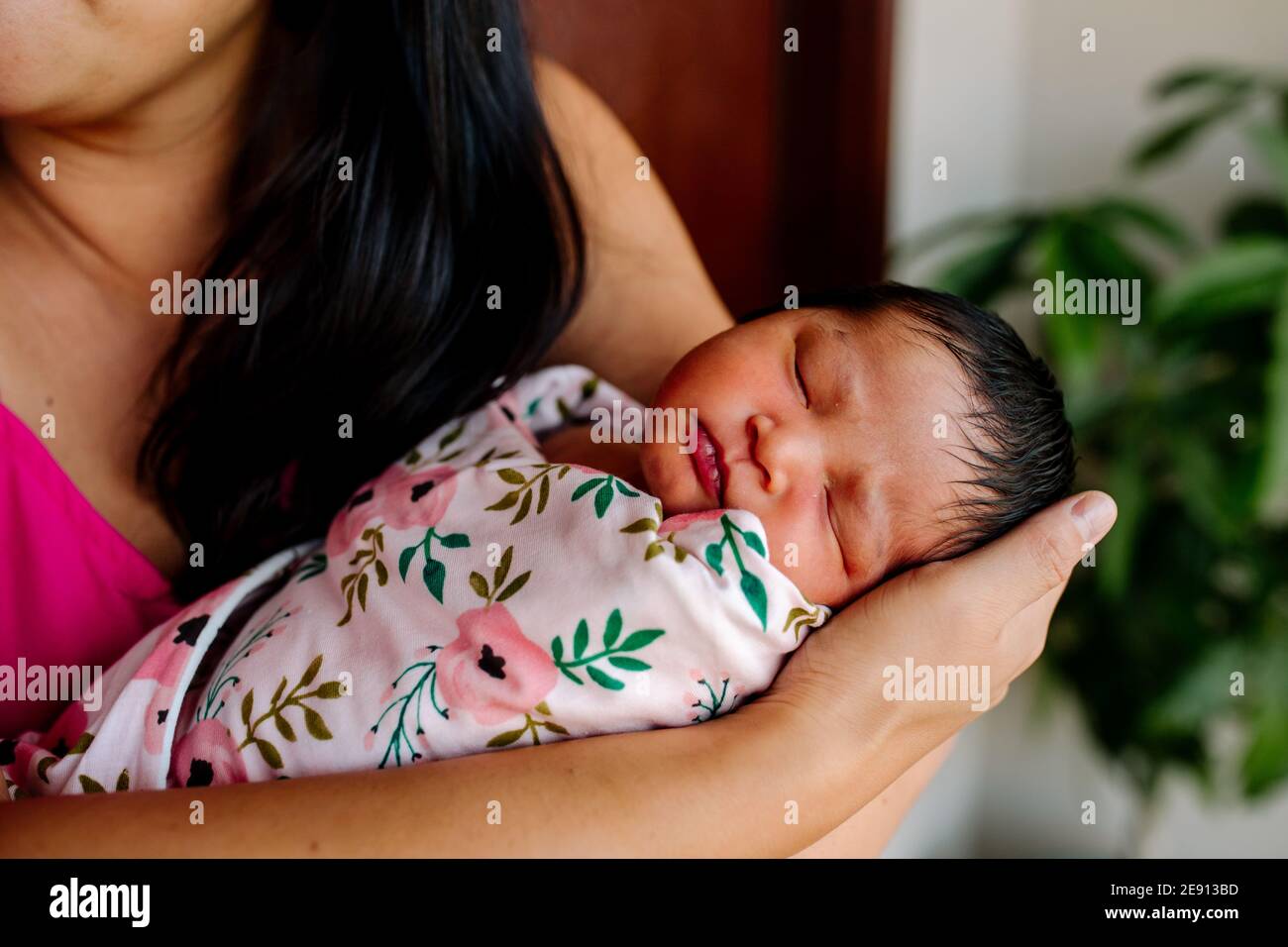 Sleeping newborn baby cradled in arms of loving mother Stock Photo - Alamy