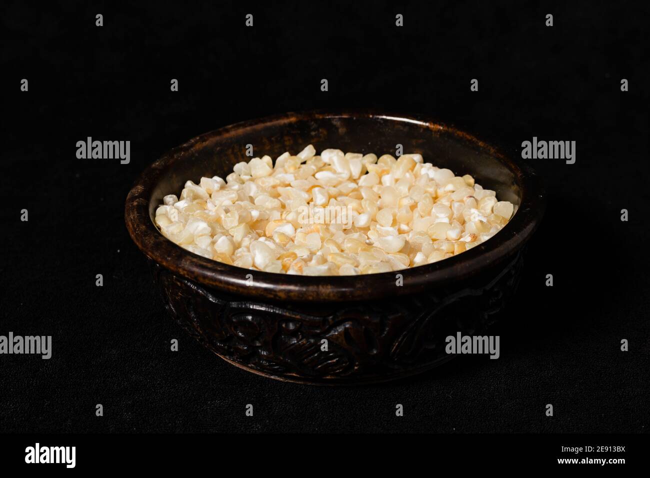 Broken white corn seeds in a wooden jar on a black surface Stock Photo ...