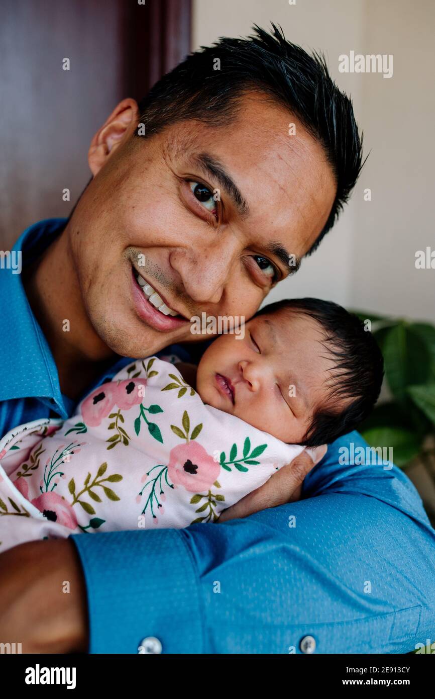 Smiling unshaven asian dad holds sleeping newborn daughter close Stock ...
