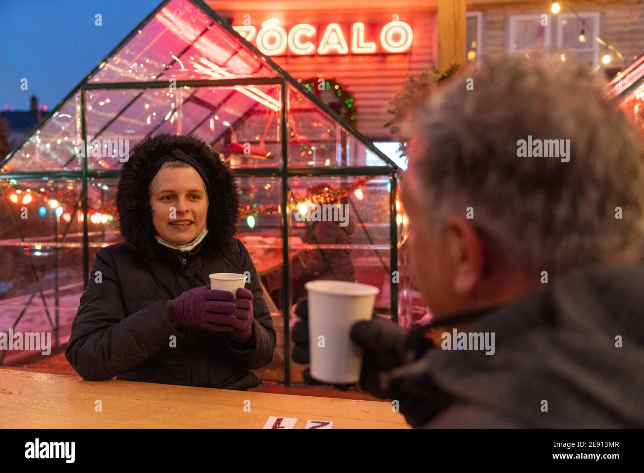 Two friends drink hot chocolates while sitting at a picnic table at an ...