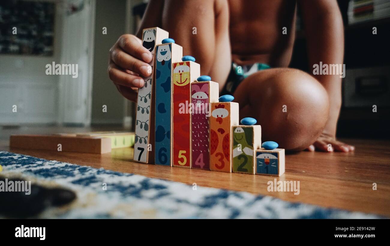 Child on the floor using colorful number blocks with animal faces to ...