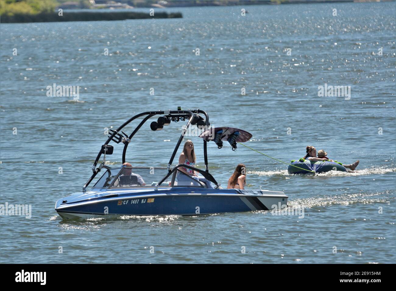 Family ski boat pulling tire inner tube with kids riding behind on a ...