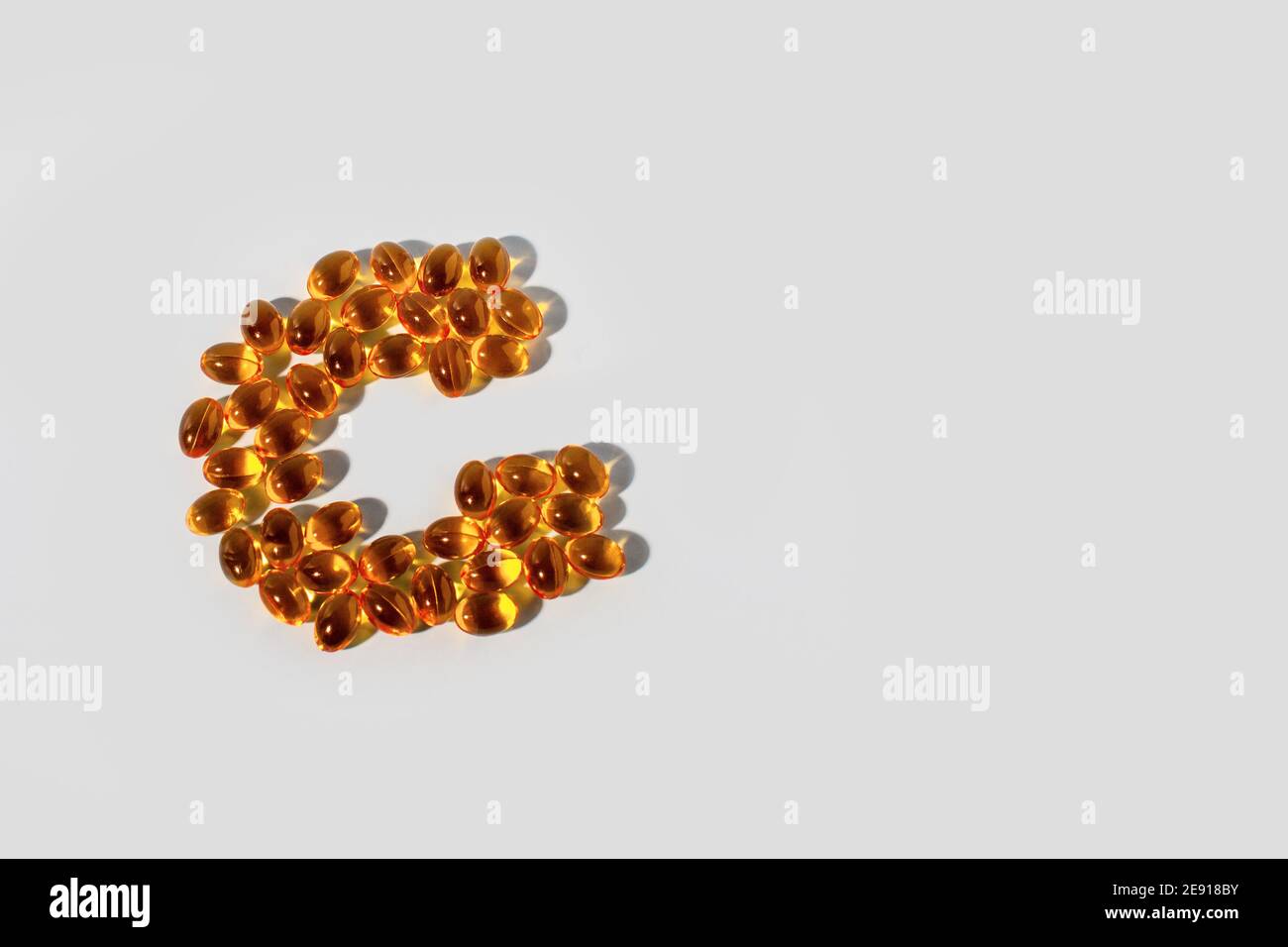 Yellow gelatin capsules on a gray background in the shape of the letter ...