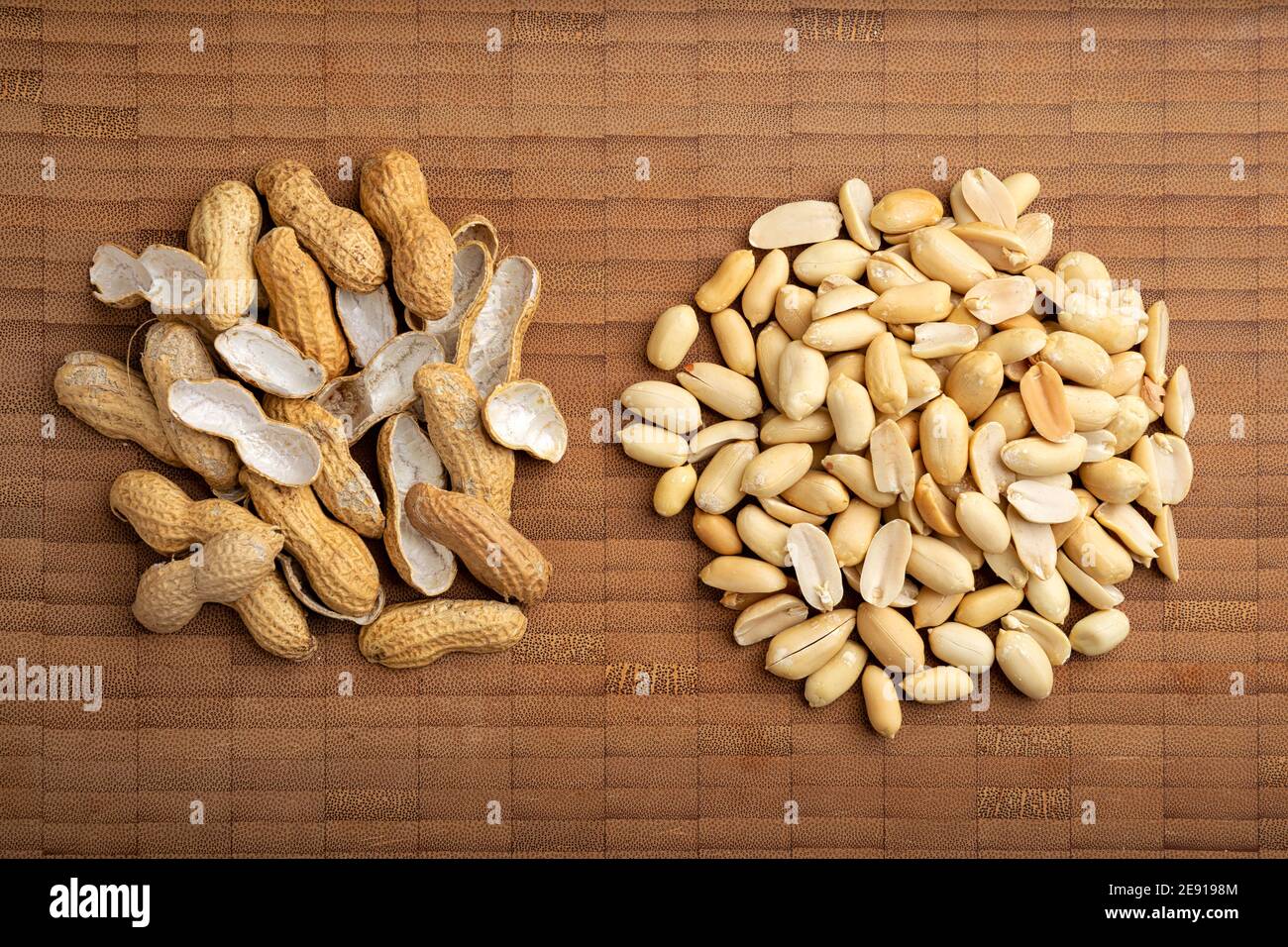 flat lay image of peeled peanuts seeds and shells on bamboo cutting ...