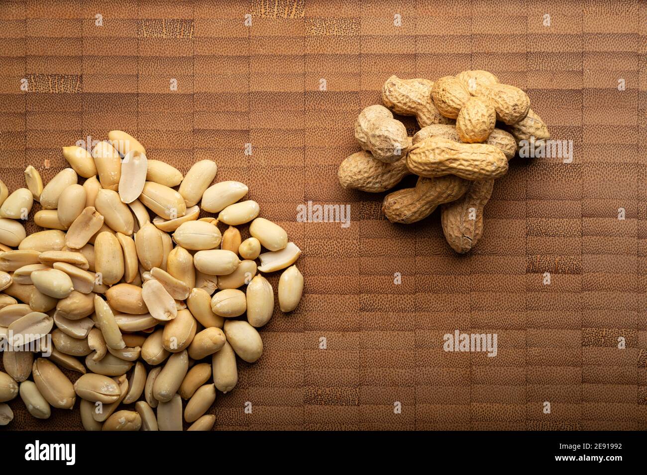 top view image of peeled and unpeeled peanuts seeds and on bamboo ...