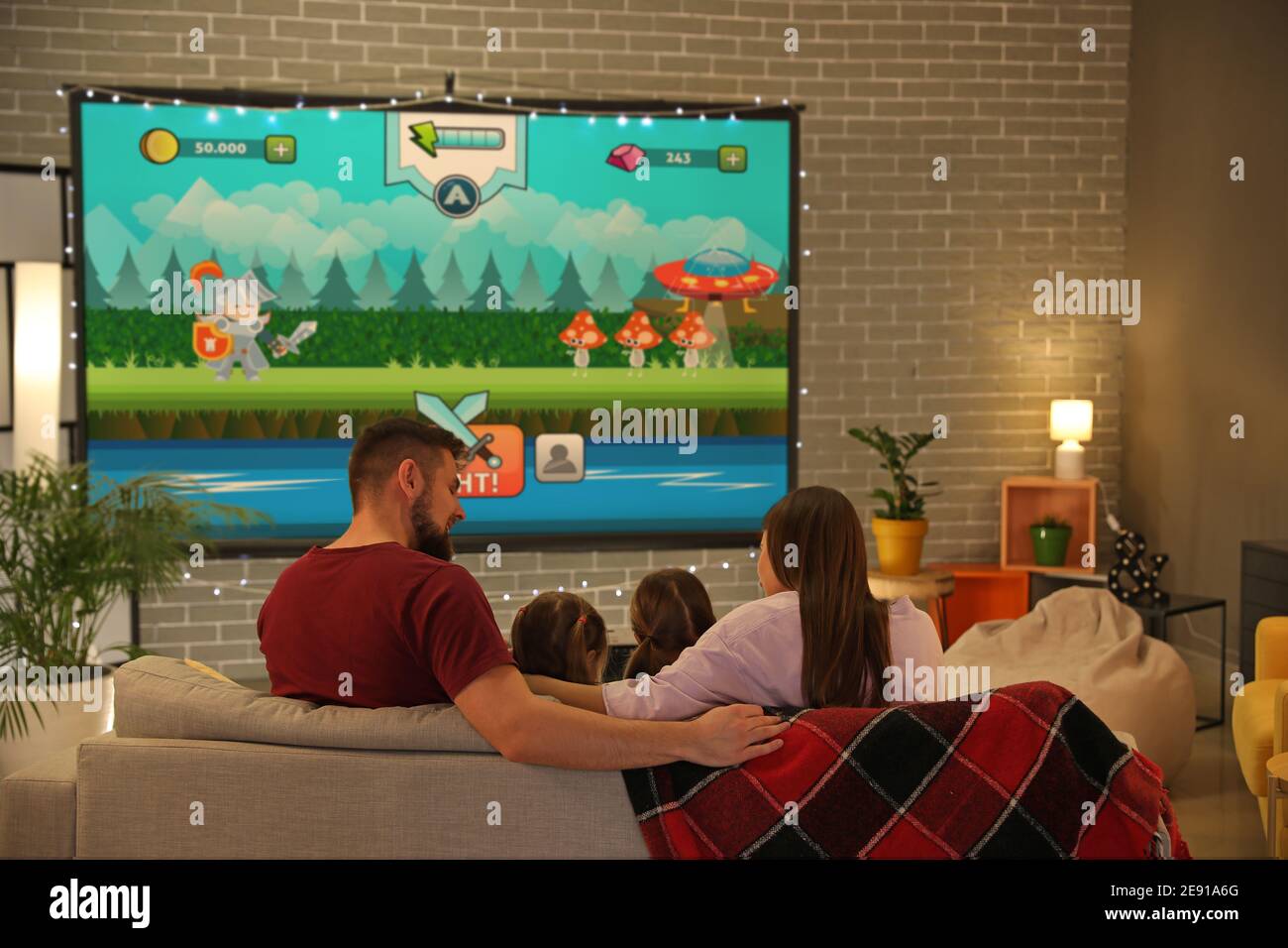 Young family playing video games on big screen at home Stock Photo - Alamy