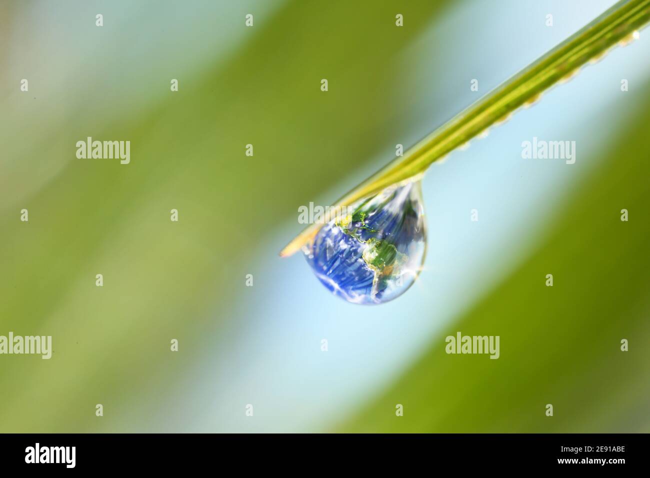 Planet Earth inside of water drop on grass, closeup. Ecology concept ...