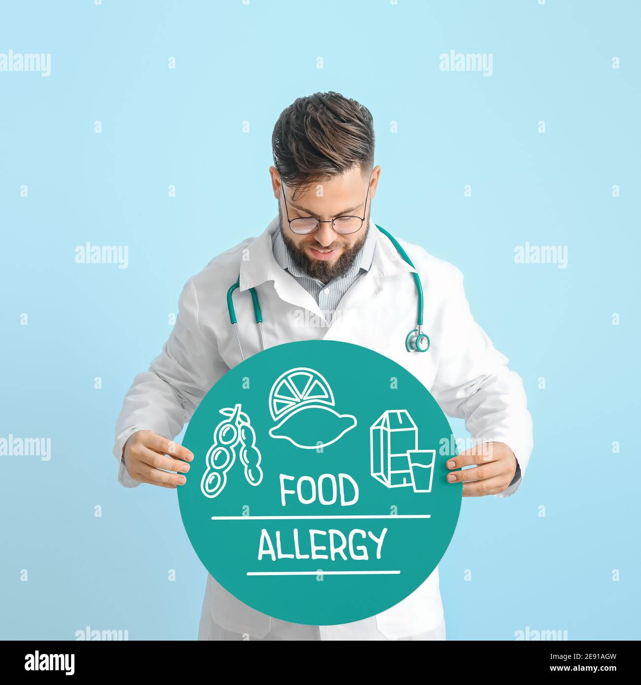 Portrait of male doctor holding poster with text FOOD ALLERGY on color ...