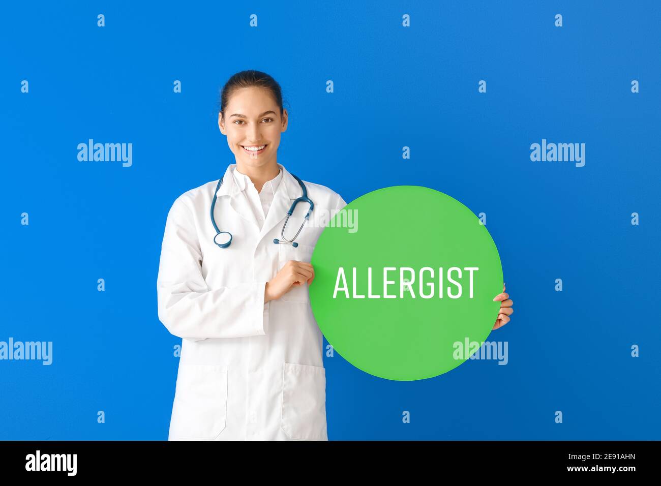 Portrait of female doctor holding poster with text ALLERGIST on color ...
