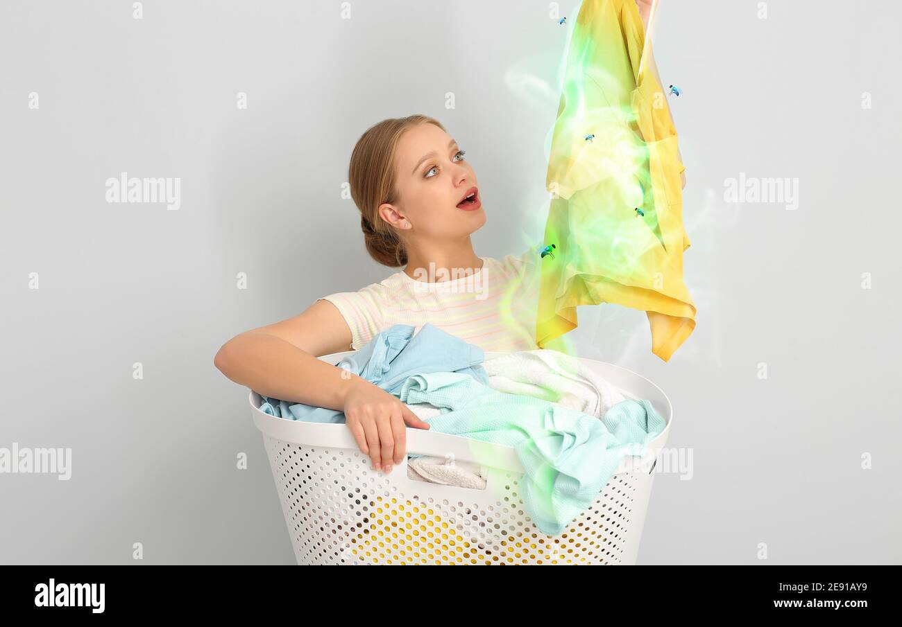 Young woman with dirty smelly laundry on grey background Stock Photo ...
