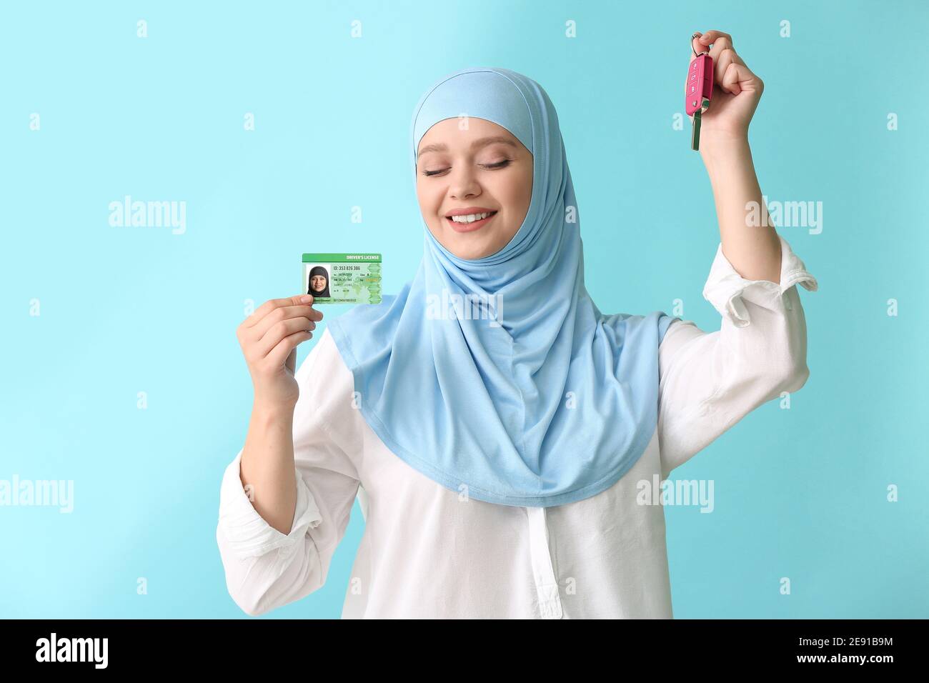Happy Muslim woman with driving license and car key on color background ...